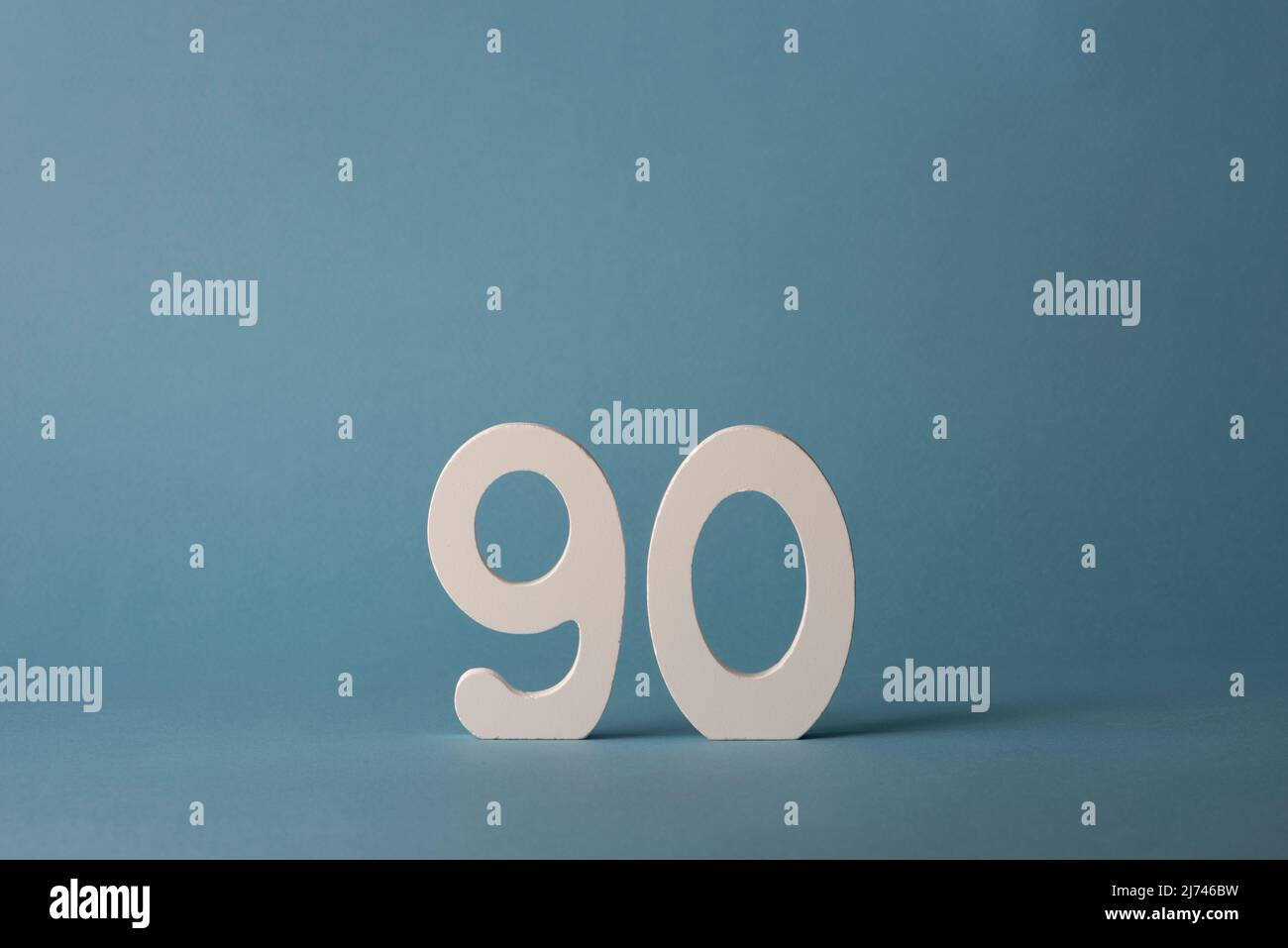White wooden number ninety 90 on blue background Stock Photo - Alamy