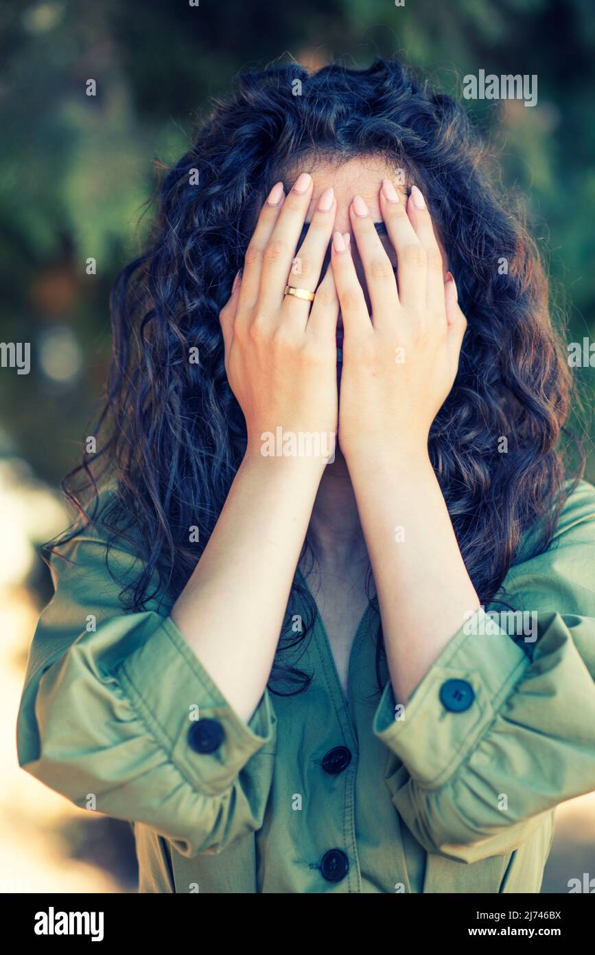 Woman hiding face with hands outdoors Stock Photo - Alamy