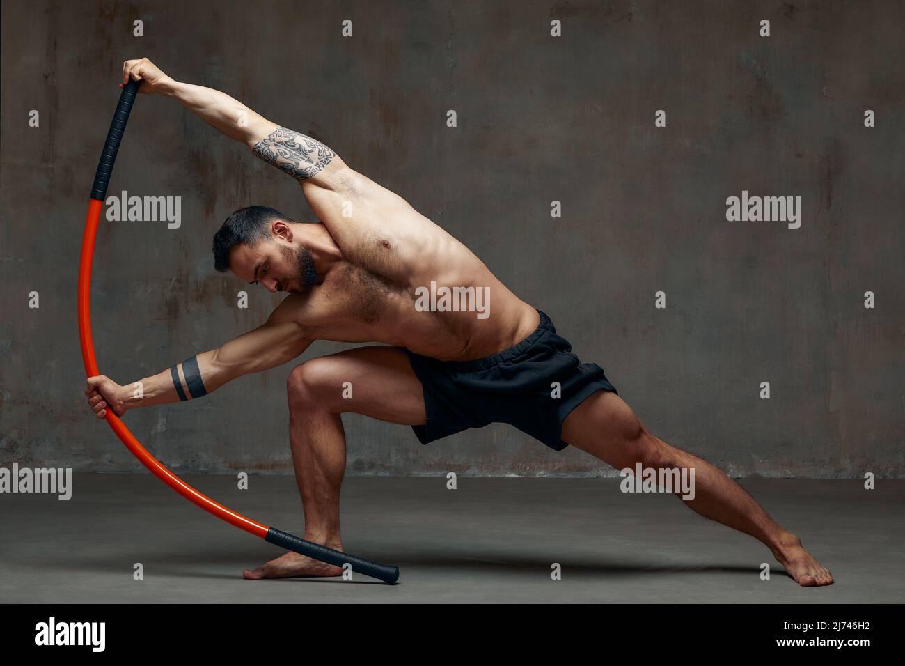 A ninja man holds on to a fighting stick and attacks close-up on gray ...