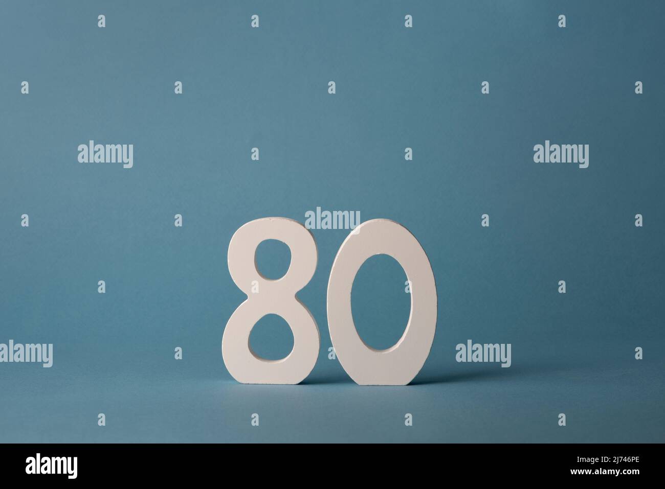 White wooden number eighty 80 on blue background Stock Photo - Alamy