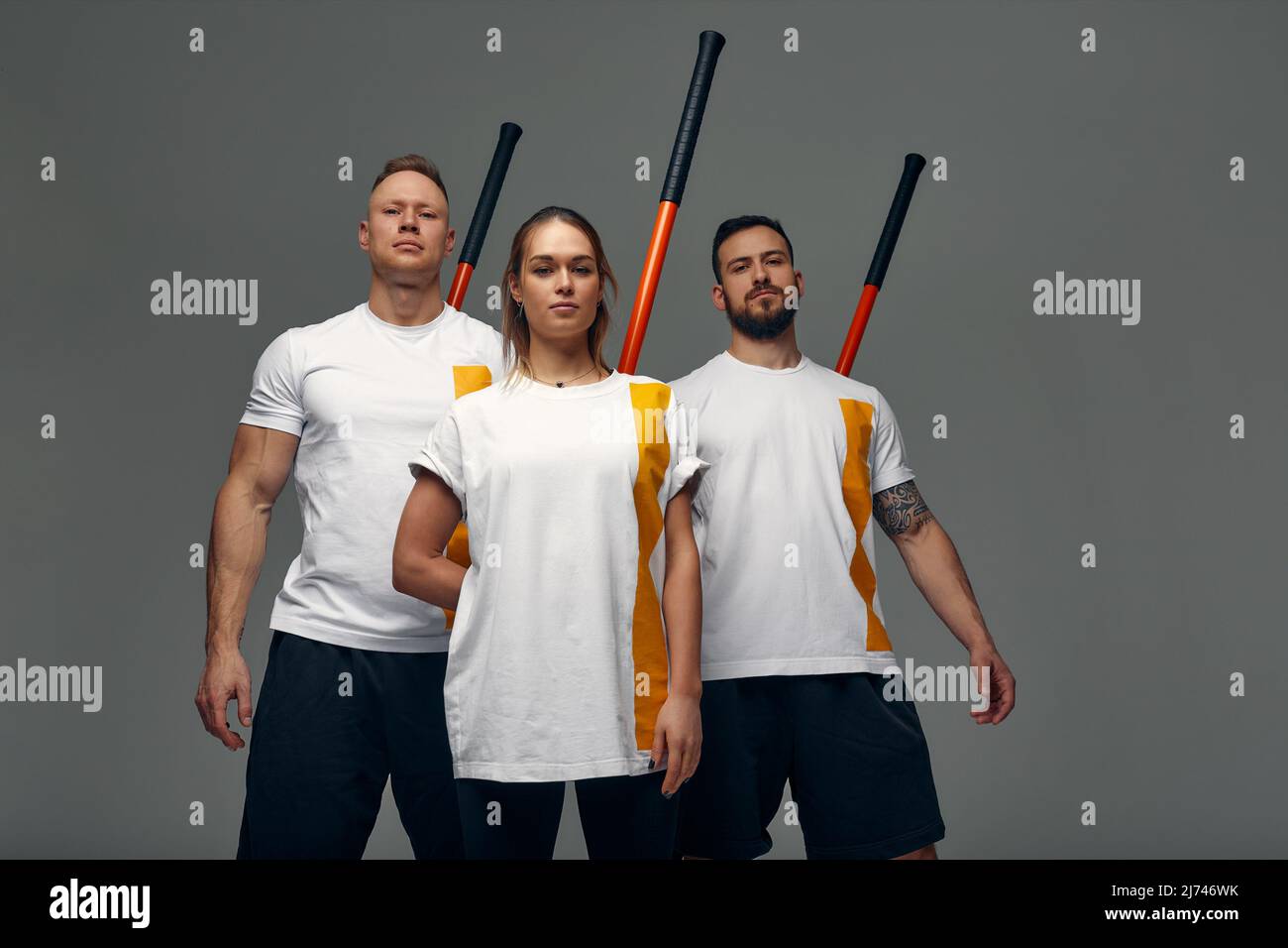 Two men and woman aikido fighters with wooden fight stick posing in ...