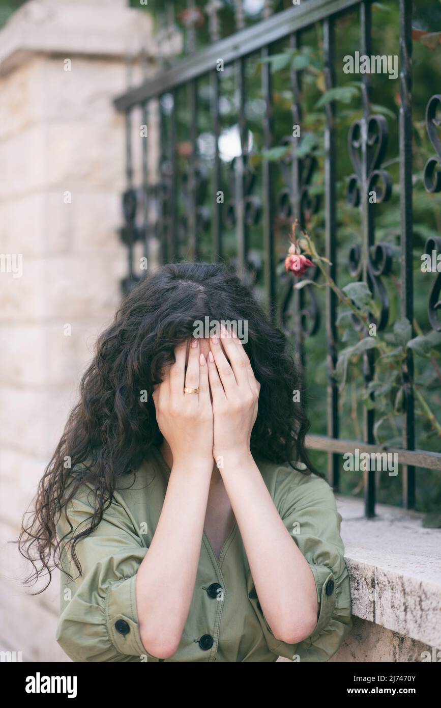 Woman hiding face with hands outdoors Stock Photo - Alamy