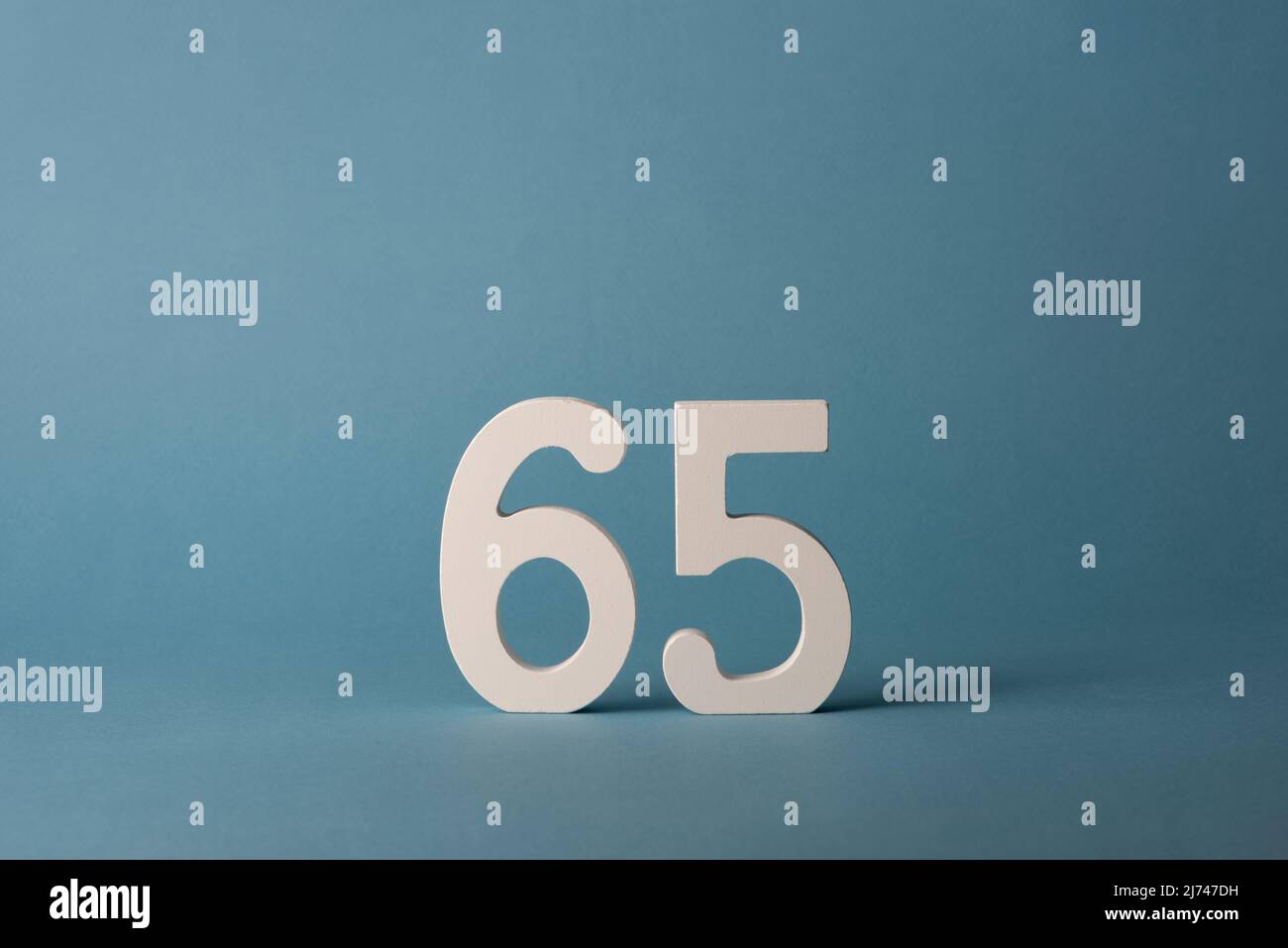 White wooden number sixty-five 65 on blue background Stock Photo - Alamy