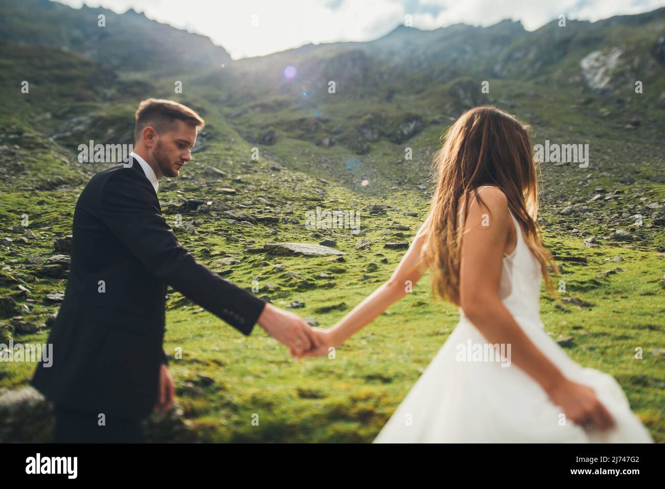 The brides walking along mountains holding hands. Bride and stylish ...