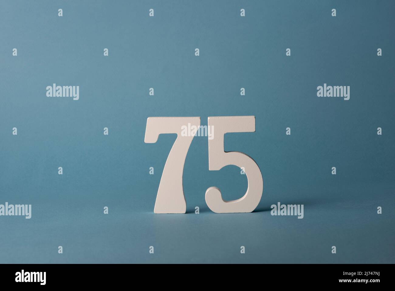 White wooden number seventy-five 75 on blue background Stock Photo - Alamy