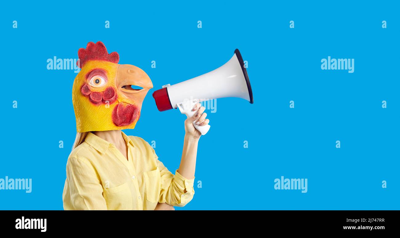 Female in rooster mask screaming into loudspeaker isolated on blue ...