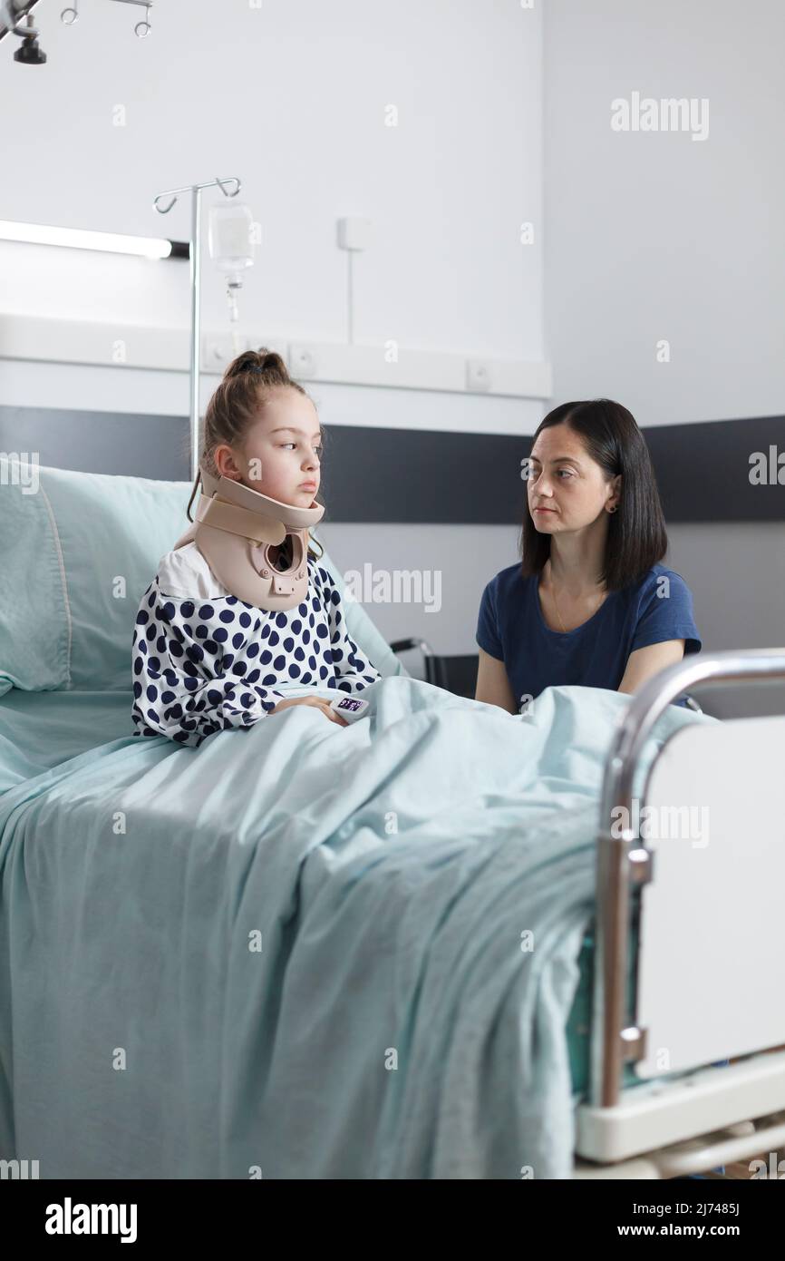 Compassionate uneasy mother spending time in hospital patient room with ...