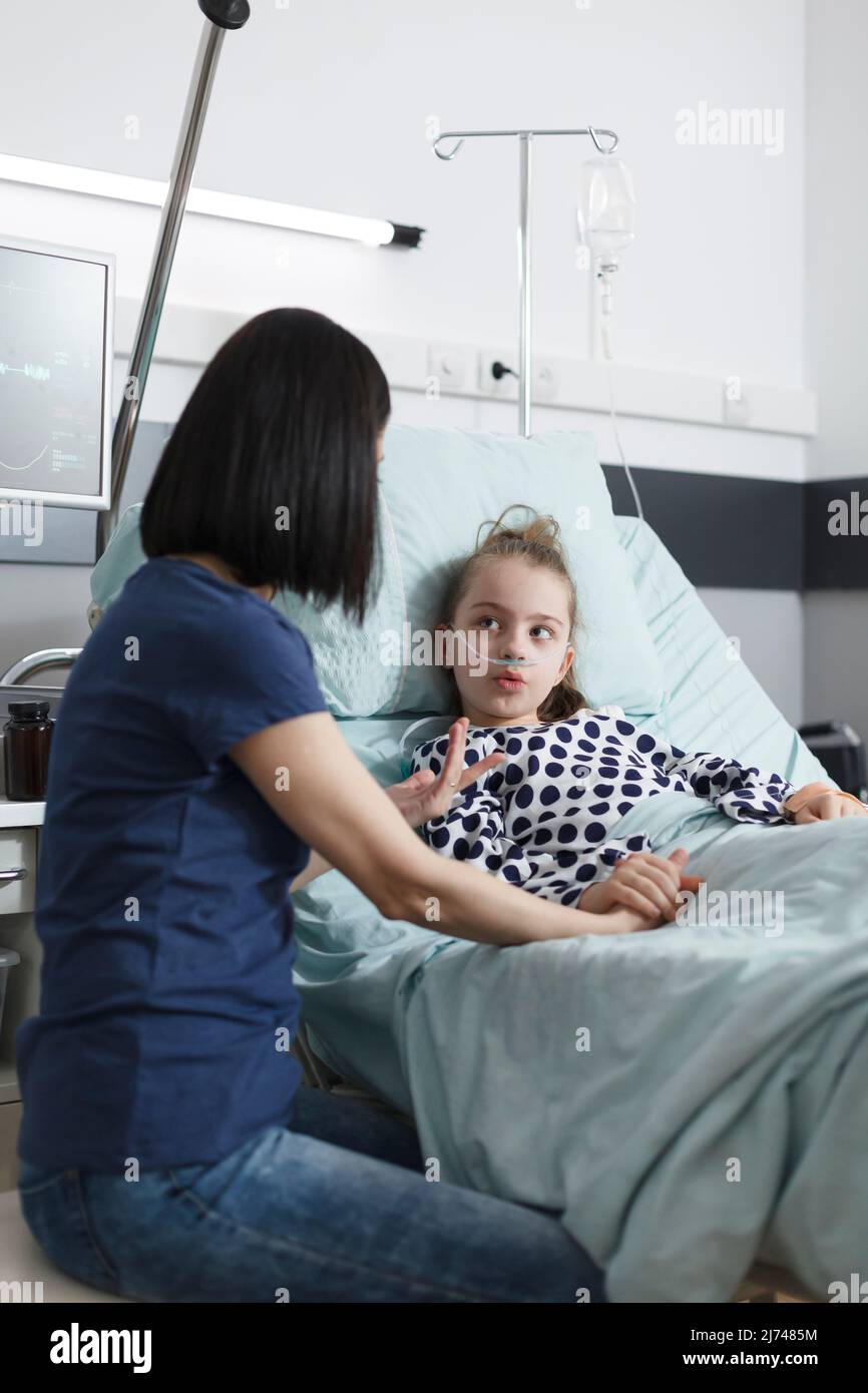 Thoughtful kind young mother talking with unwell little daughter while offering emotional ...