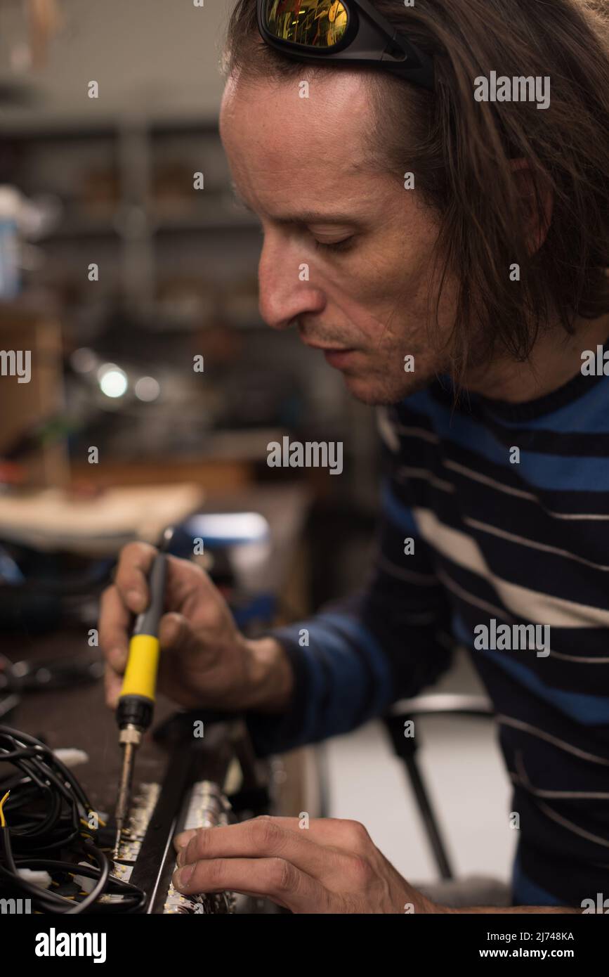 Industrial worker man soldering cables of manufacturing equipment in a ...