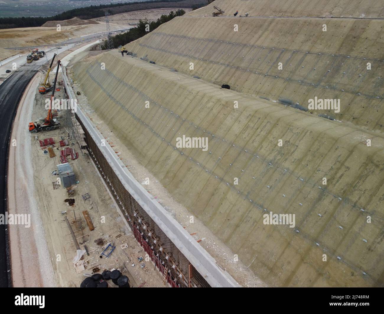 Workers reinforce the slope over the new road. Road construction in ...