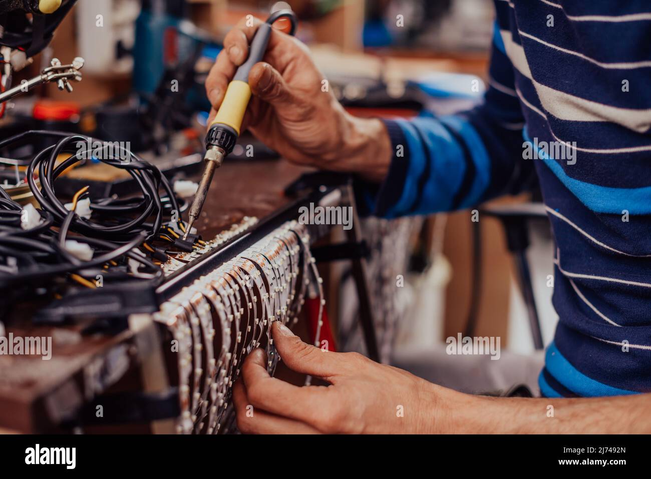 Industrial worker man soldering cables of manufacturing equipment in a ...