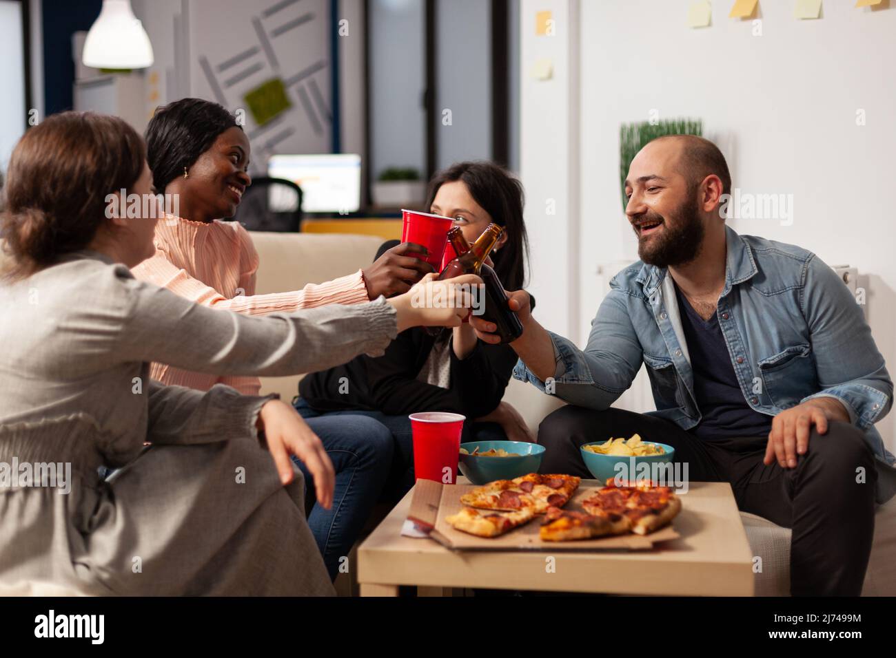 Diverse group of workmates clinking glasses and bottles at office ...