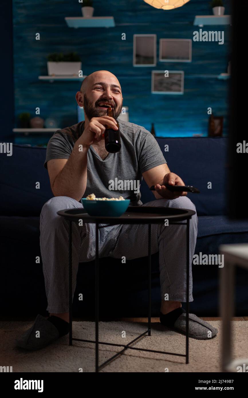 Happy man watching funny movie on TV program and laughing, enjoying ...