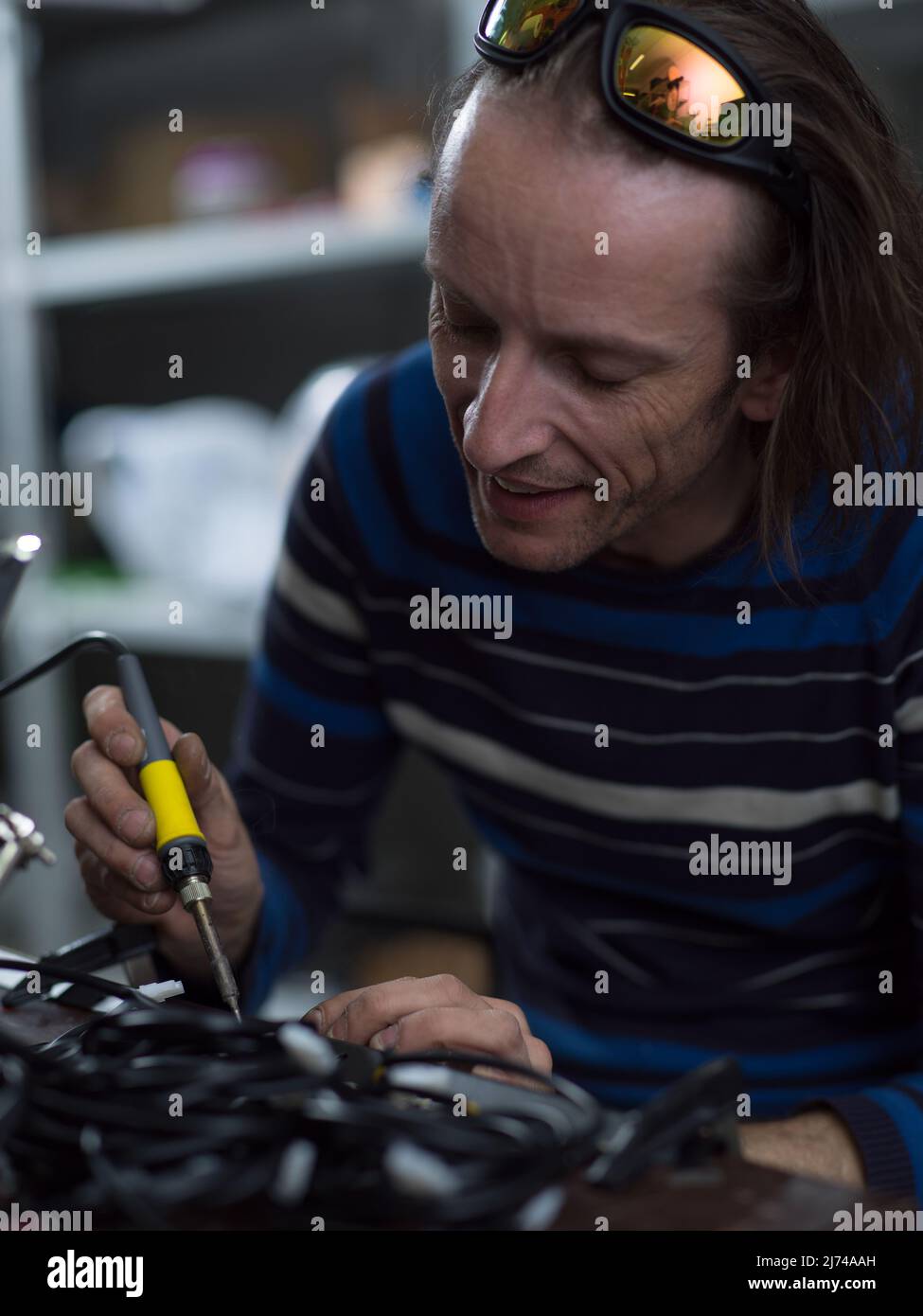 Industrial worker man soldering cables of manufacturing equipment in a ...