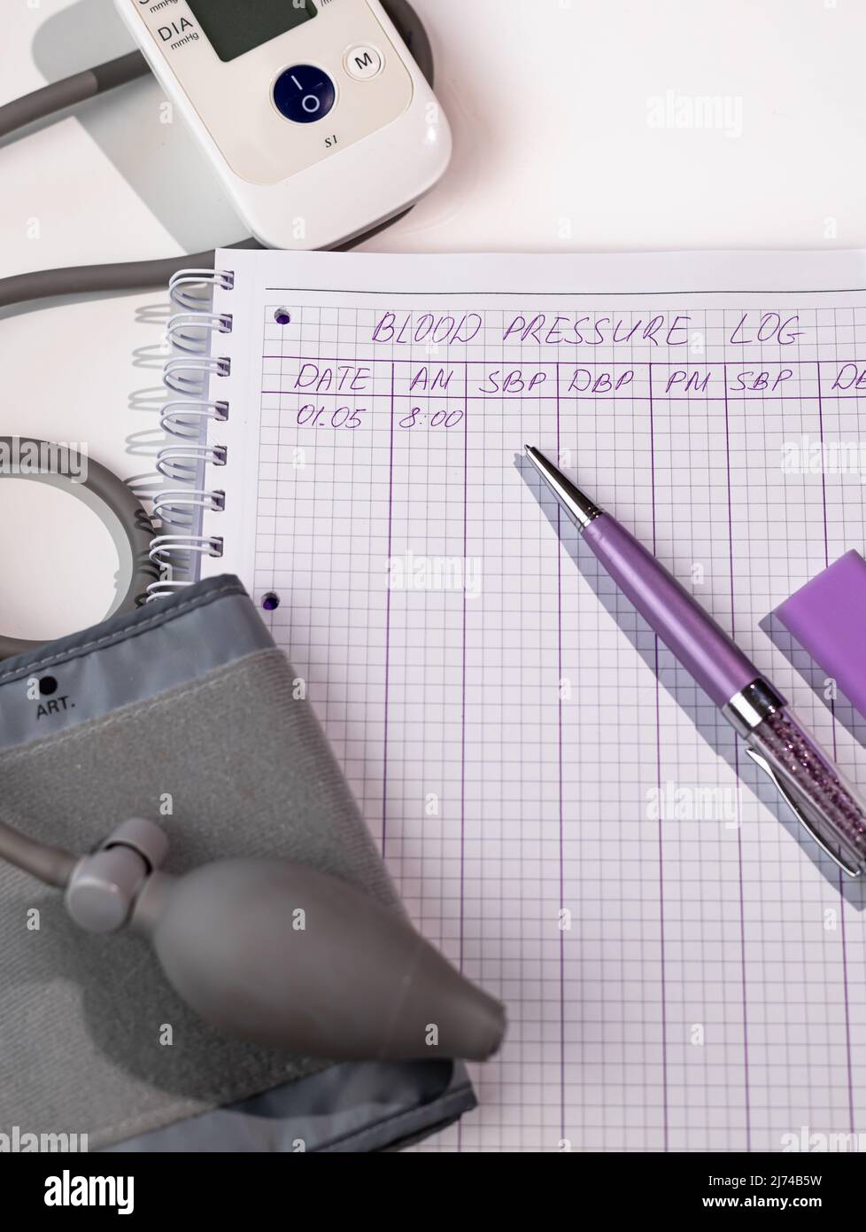Blood pressure log with pen and Blood pressure monitor on white table ...