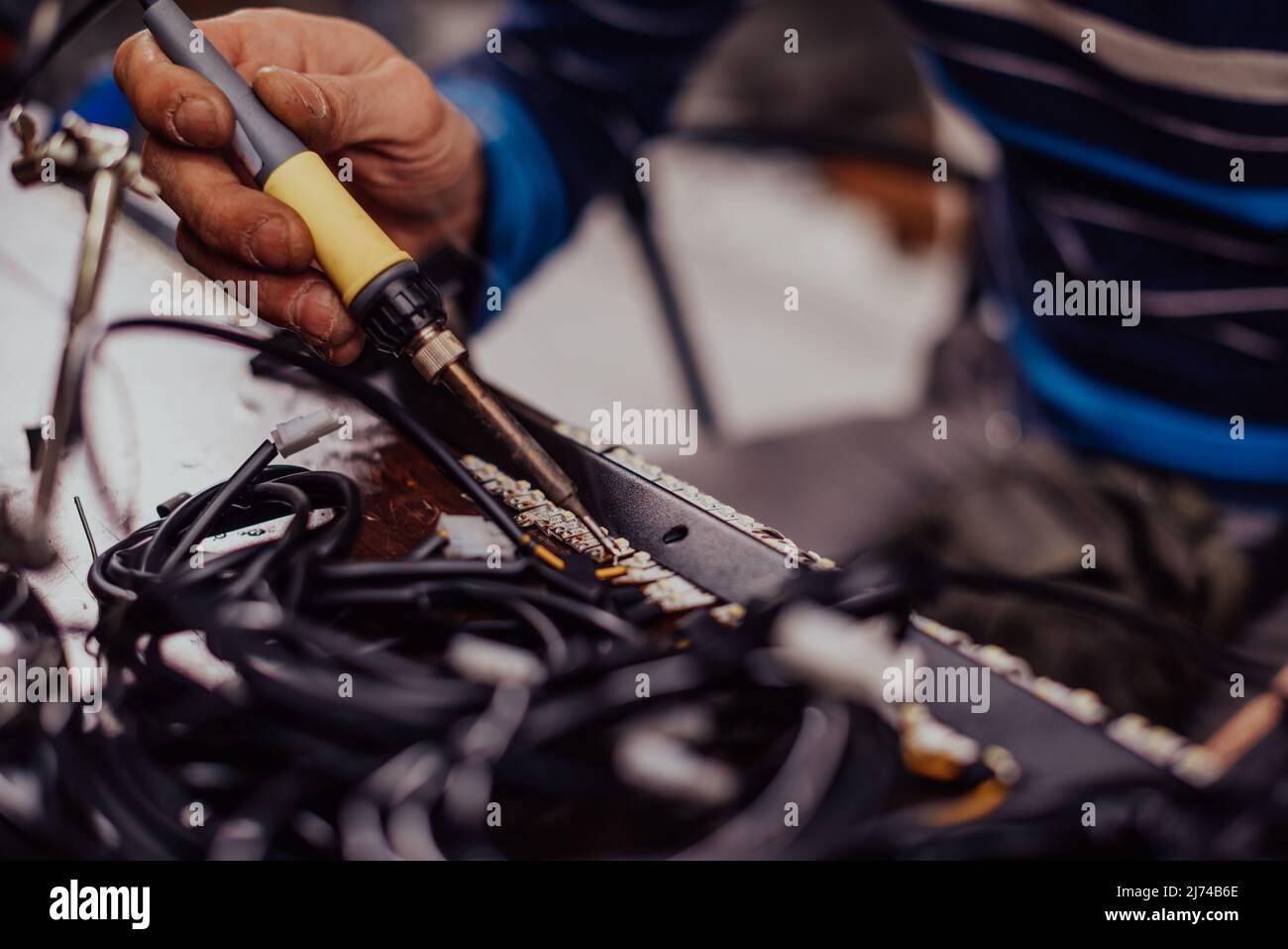 Industrial worker man soldering cables of manufacturing equipment in a ...