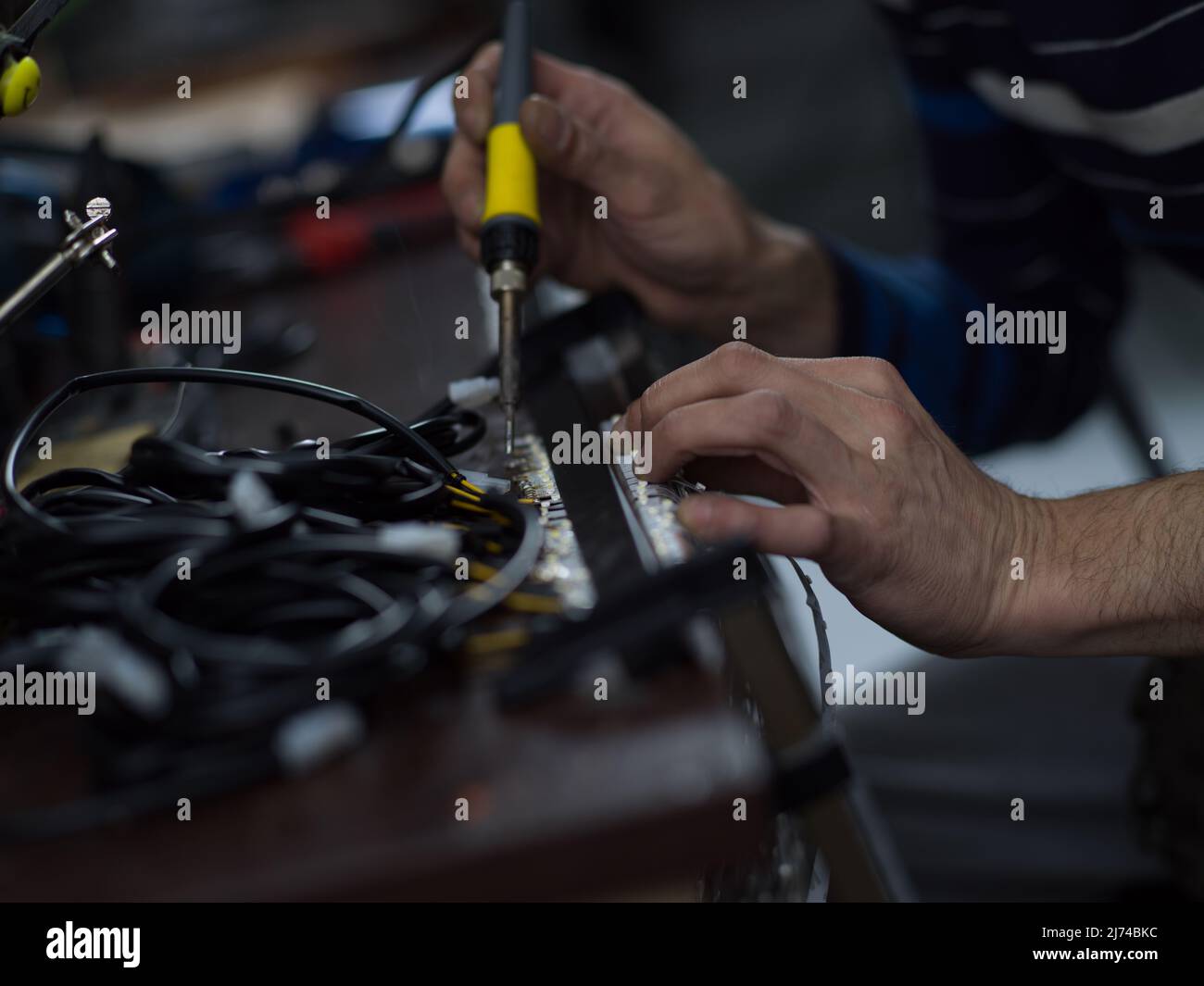 Industrial worker man soldering cables of manufacturing equipment in a ...
