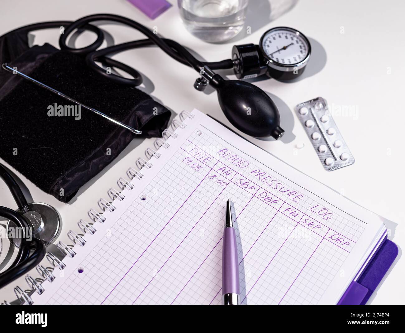 Blood pressure log with pen and Blood pressure monitor on white table ...