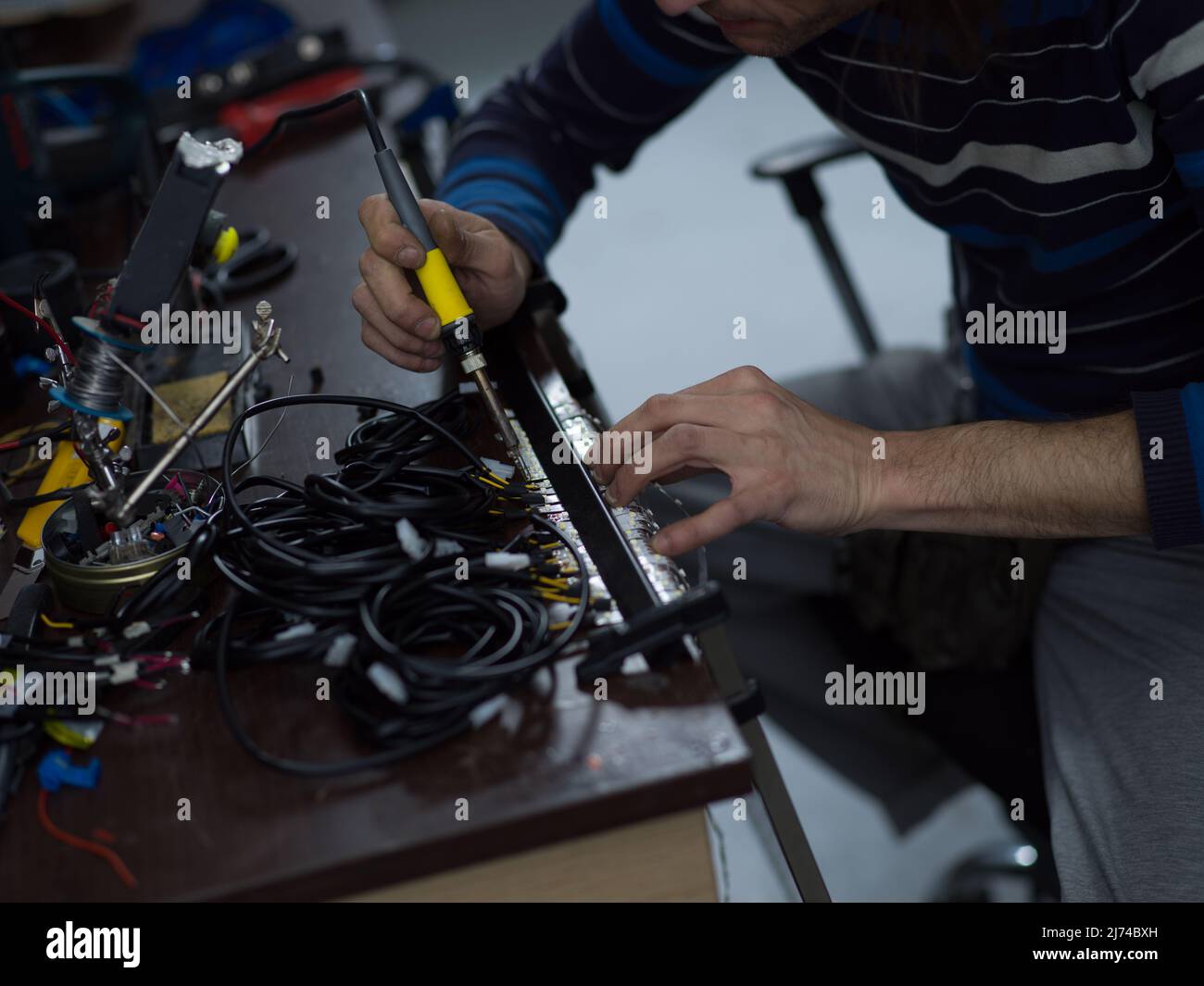 Industrial worker man soldering cables of manufacturing equipment in a ...