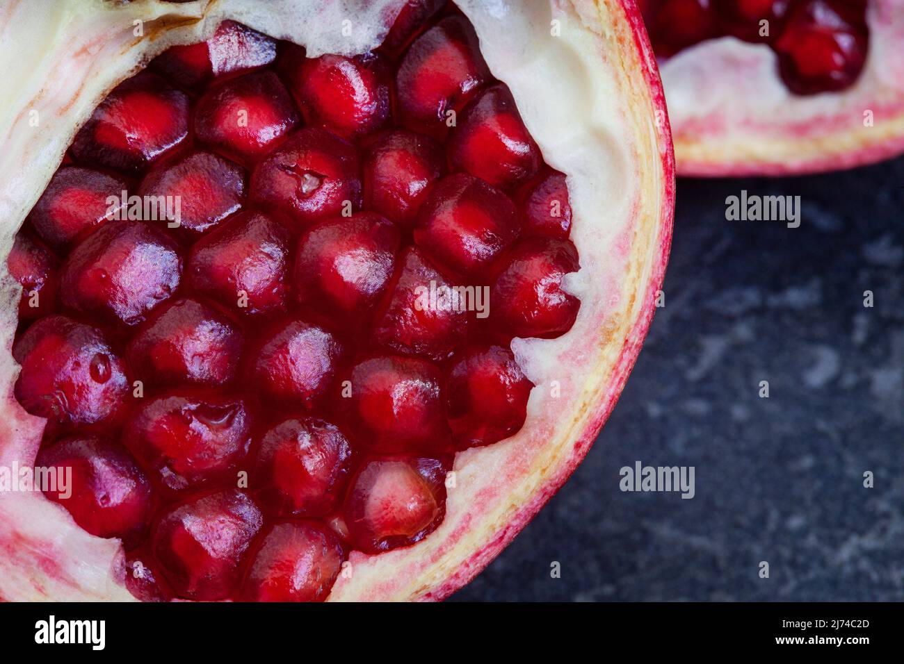 Pomegranate split open with pips on a grunge surface with copy space ...