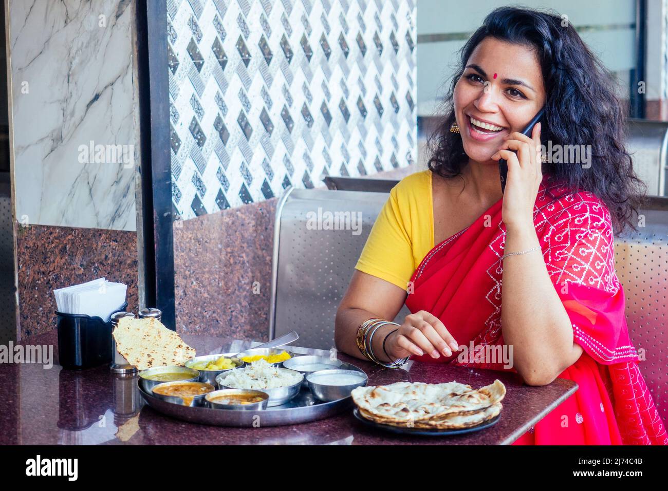 beautiful brunette woman in red sari eating with appetite traditional ...