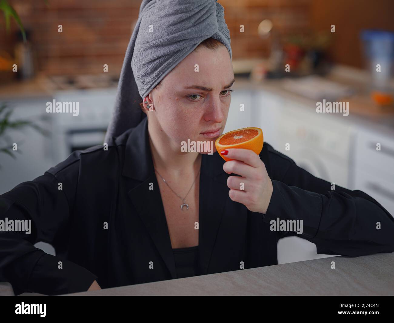 Sick woman trying to sense smell of fresh orange, has symptoms of Covid ...