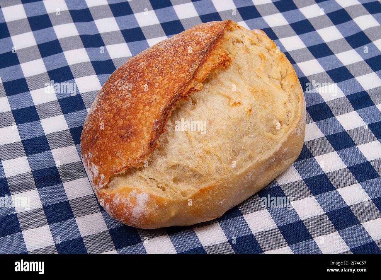 Whole loaf of freshly baked Scoring bread on checkered blue white ...
