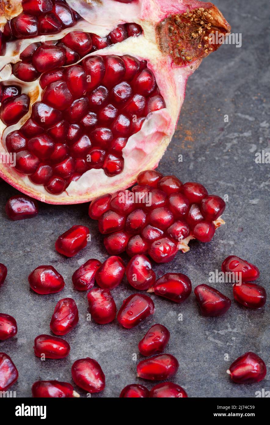 Pomegranate split open with pips on a grunge surface with copy space ...