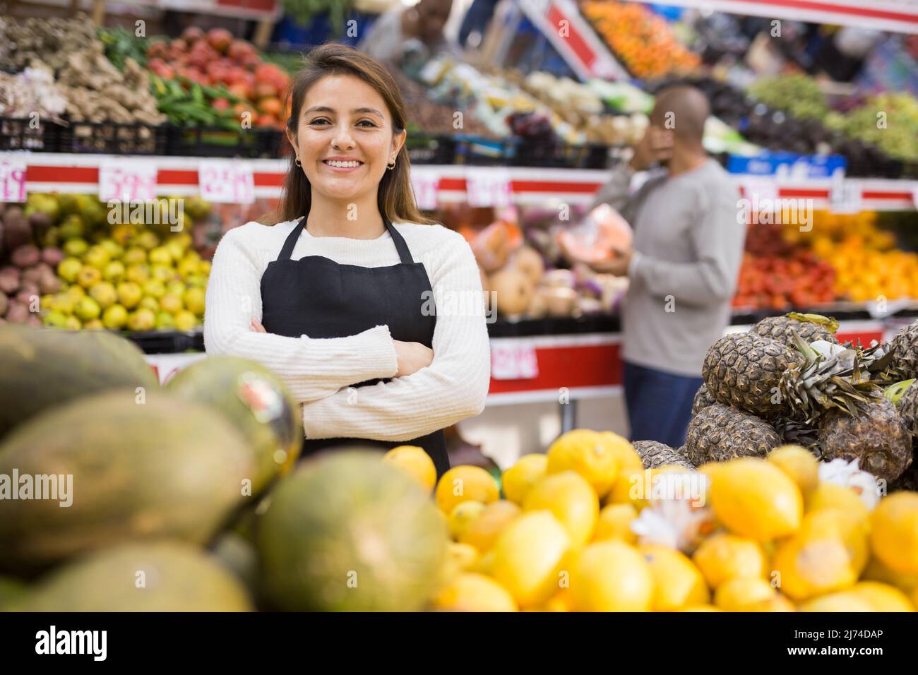 Portrait of positive female merchandiser with melon in hands at ...