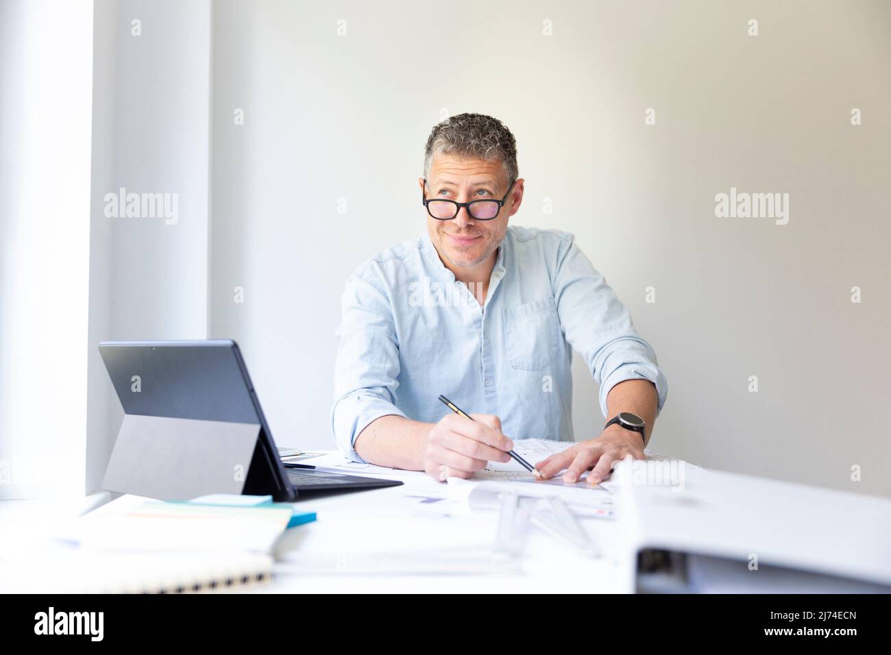 Business portrait of architect sitting at his work table and planning ...