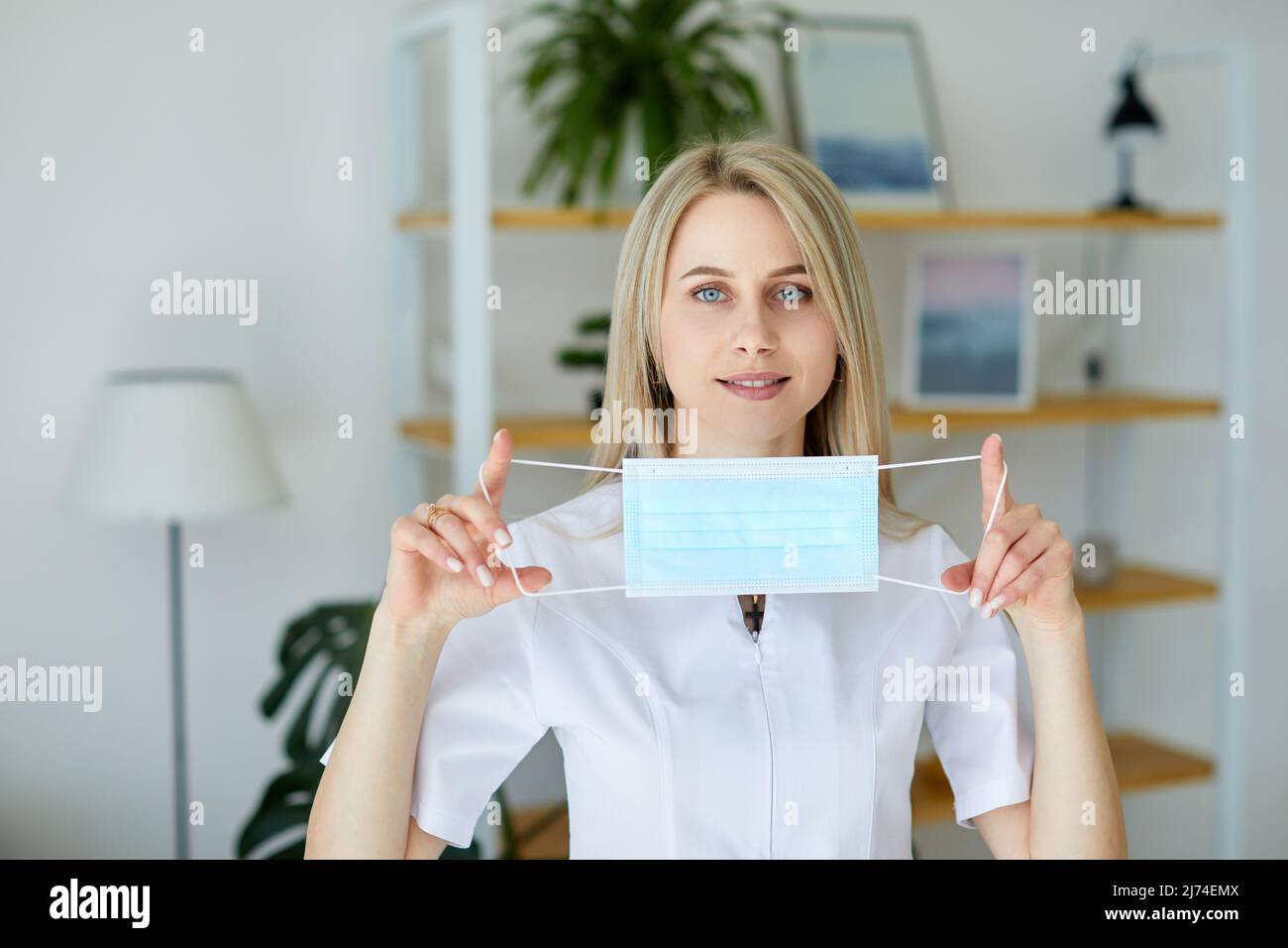 Woman healthcare professional demonstrating proper donning of mask for ...
