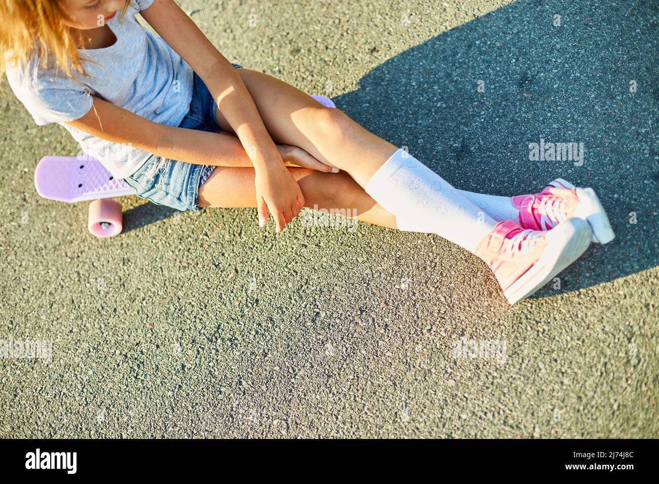 Little girl learning to use a skateboard, anonymous child wearing white ...