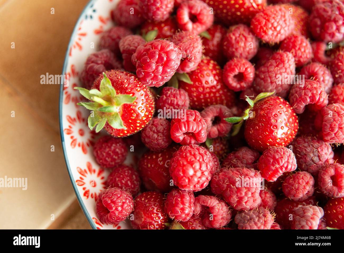 Top view of a plate of fresh strawberries and raspberries in a kitchen ...