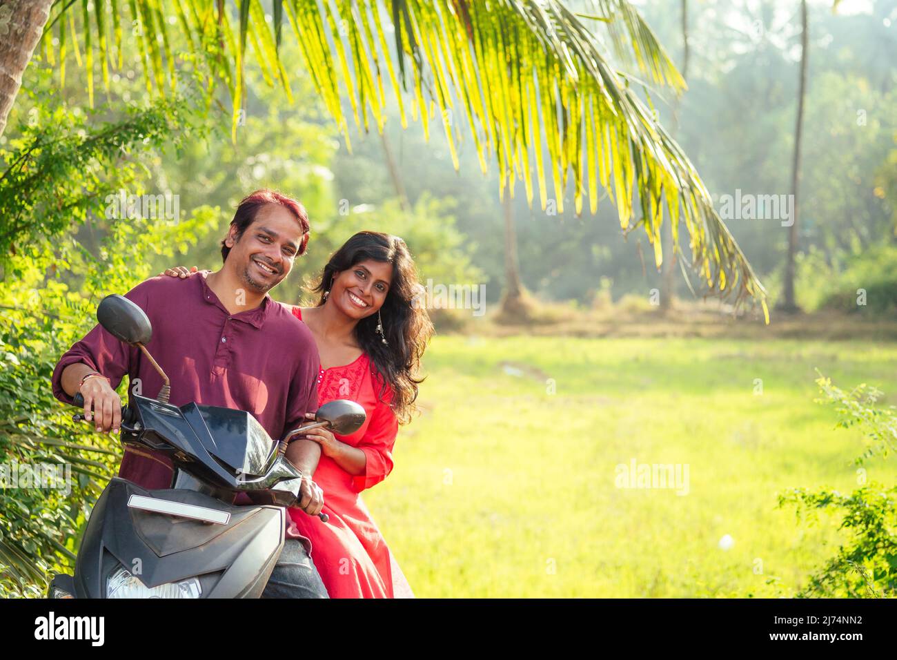 happy indian married couple riding on motorbike adventure in tropical ...