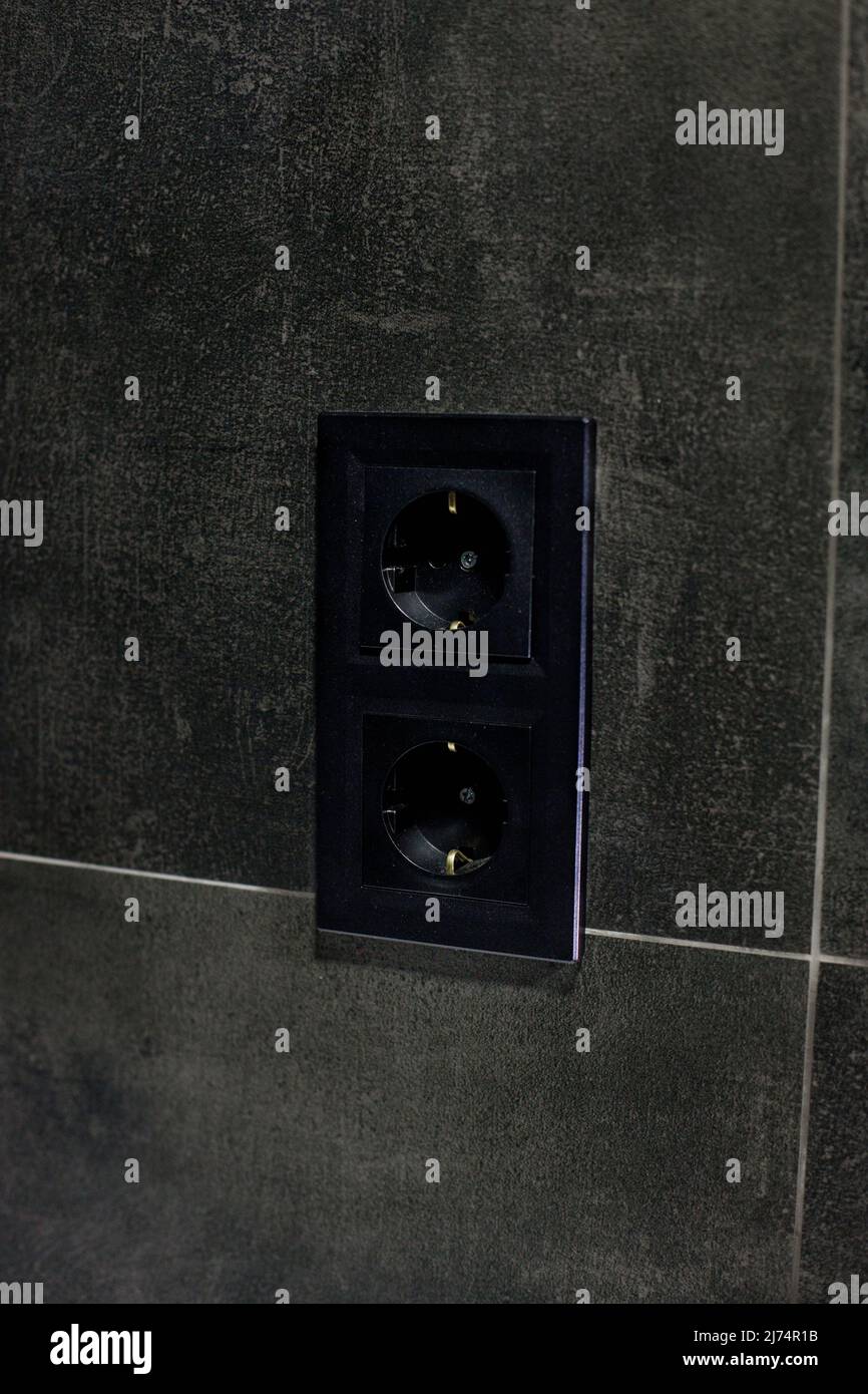 New black rosette on a ceramic tile of black color. Electrical outlet ...