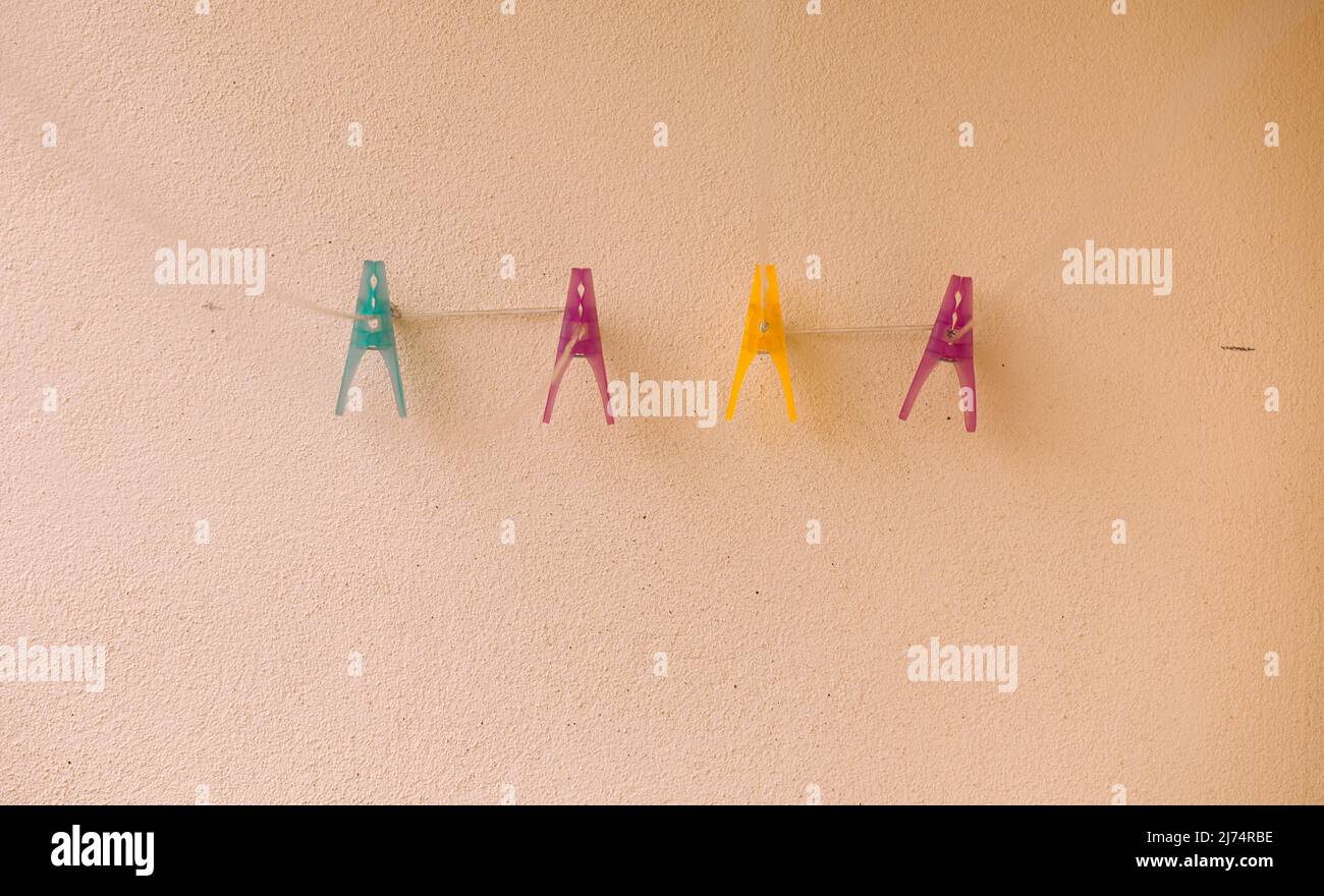 Blue purple yellow clothes pegs hang on the washing line and stand out ...