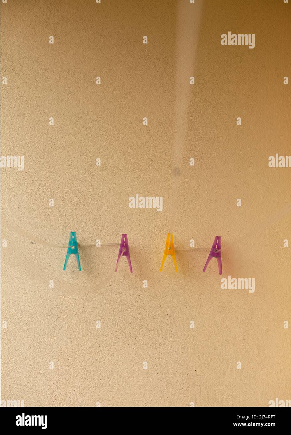 Blue purple yellow clothes pegs hang on the washing line and stand out ...