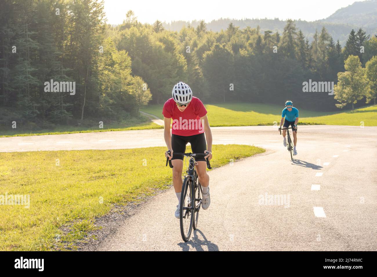 Female athlete on a racing bicycle riding uphill an asphalt road at ...