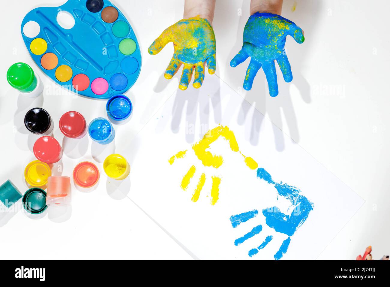 Children's handprints. Blue and yellow palm prints on a white sheet of ...