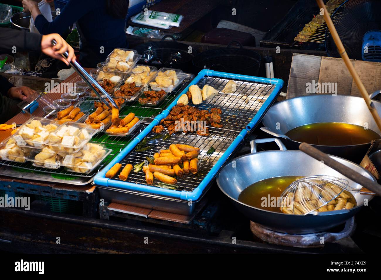 Thai chef marchant cooking deep fried spring roll and fried fish patty ...
