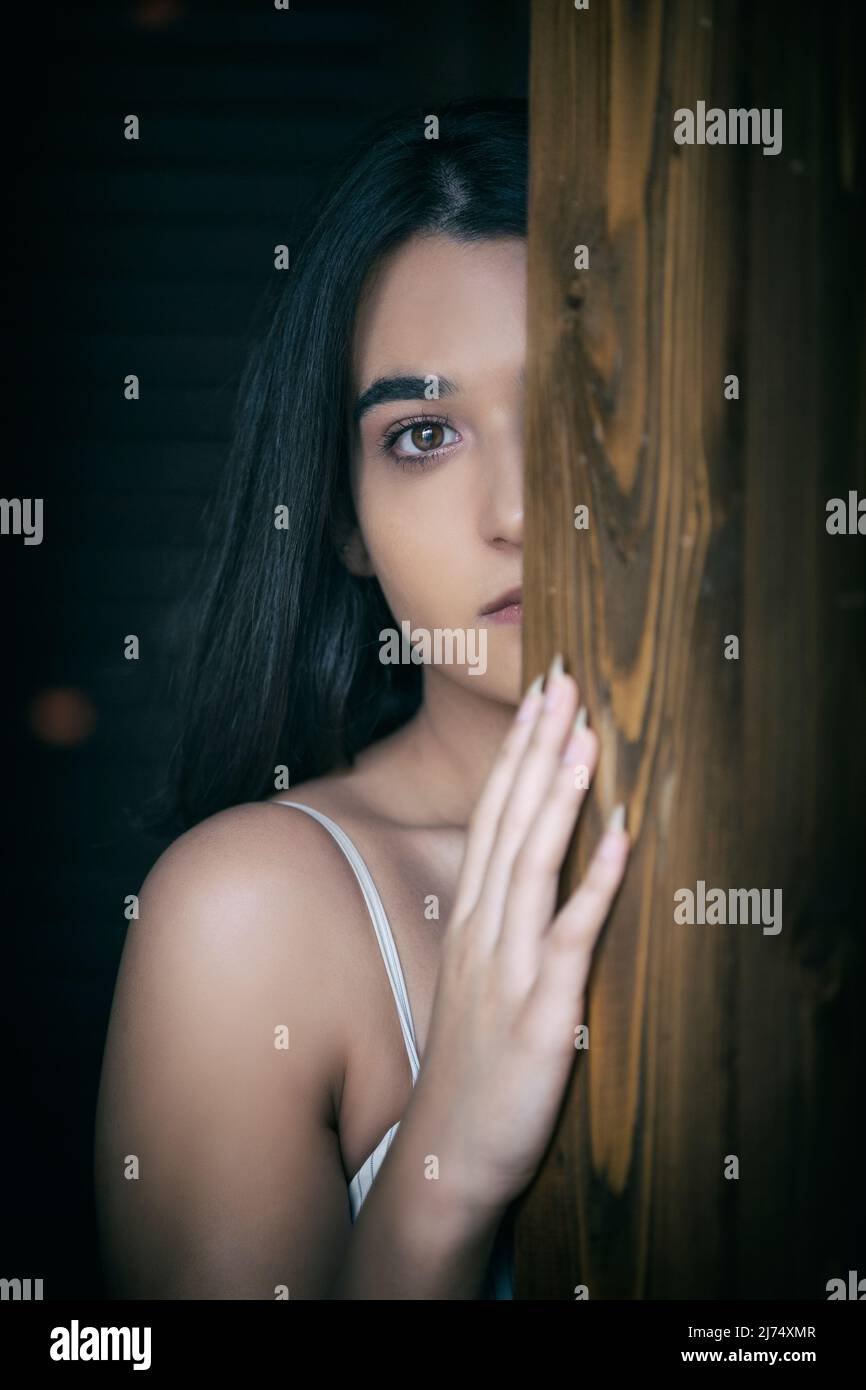 Woman in danger hiding behind the door Stock Photo - Alamy