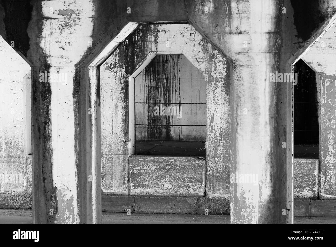 Arcade of concrete columns hold up the railroad bridge in black and ...
