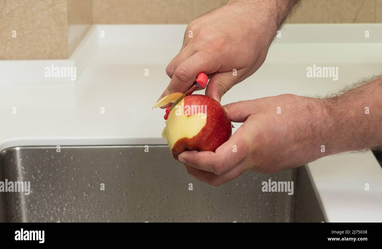 red apple being peeled over the sink by a man Stock Photo - Alamy