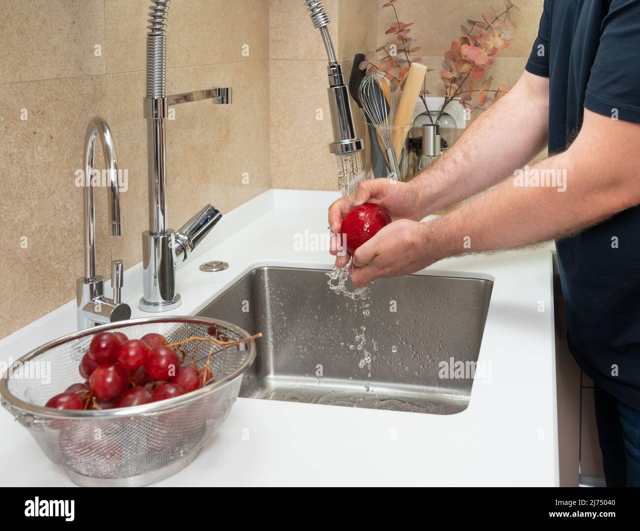 washing apples from a basket in the kitchen male hands Stock Photo - Alamy