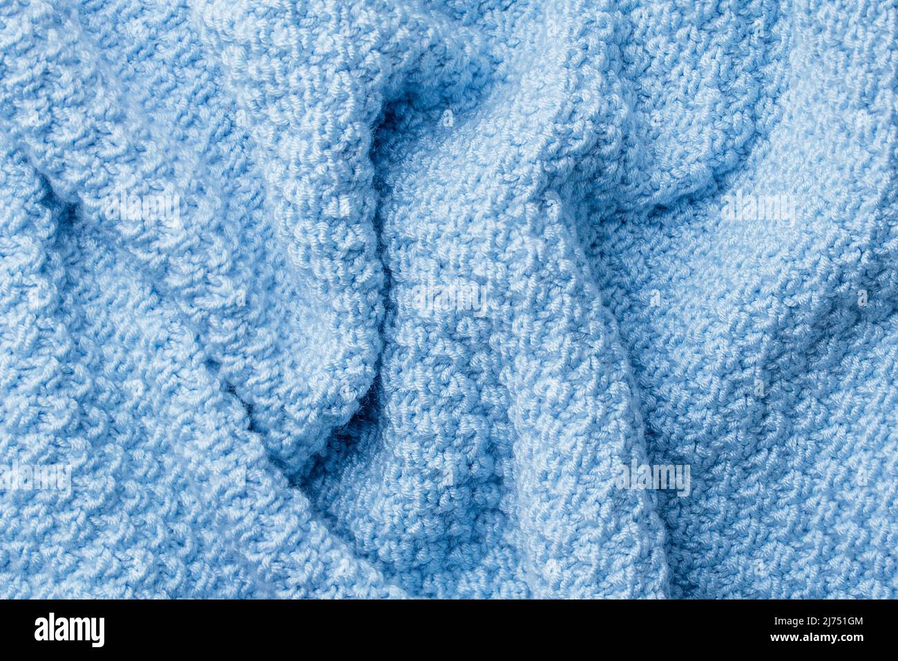 Knit texture of blue wool knitted fabric with pattern background. Place for text. close up of ...