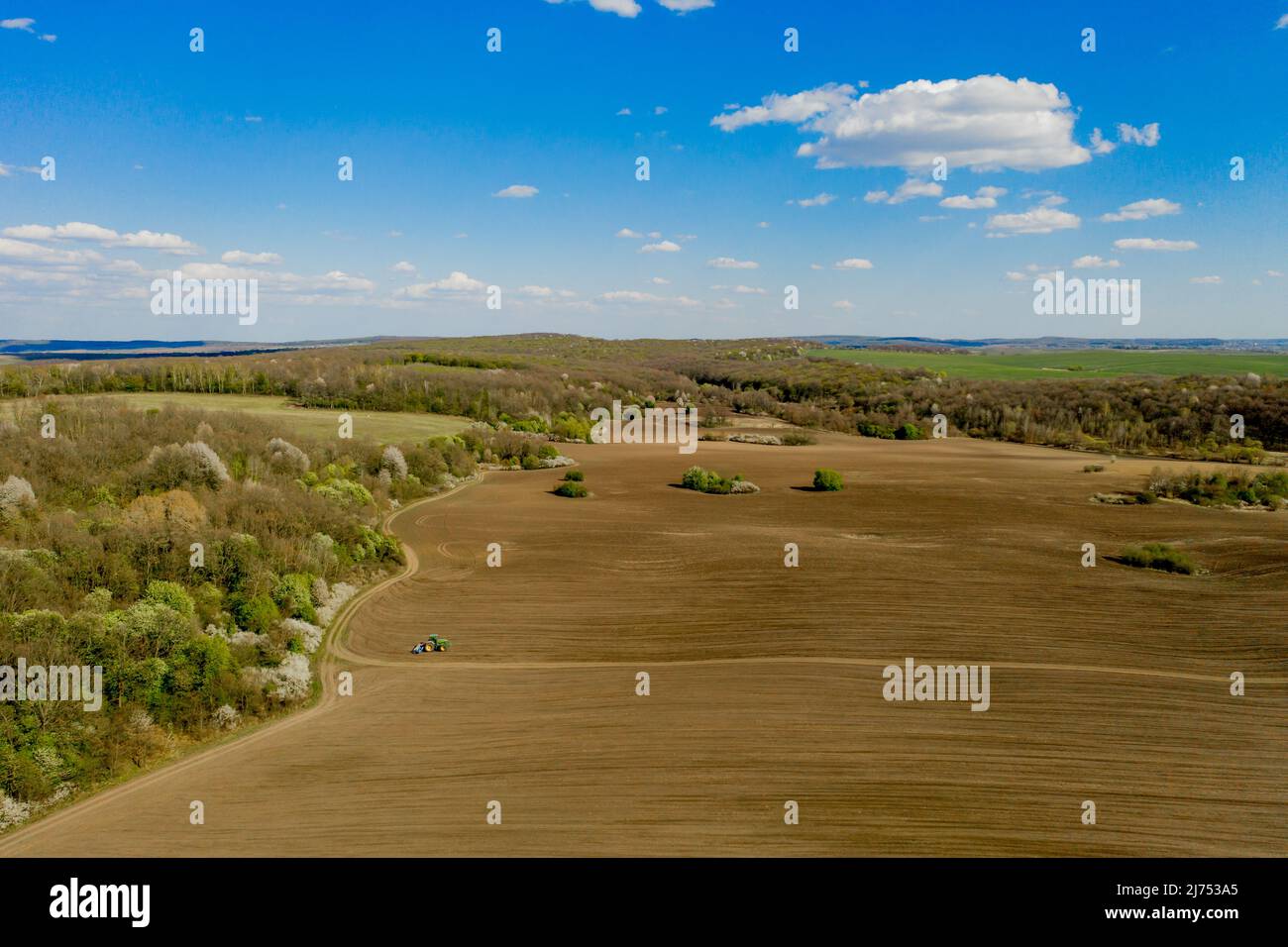 Aerial view large tractor cultivating a dry field. Top down aerial view ...
