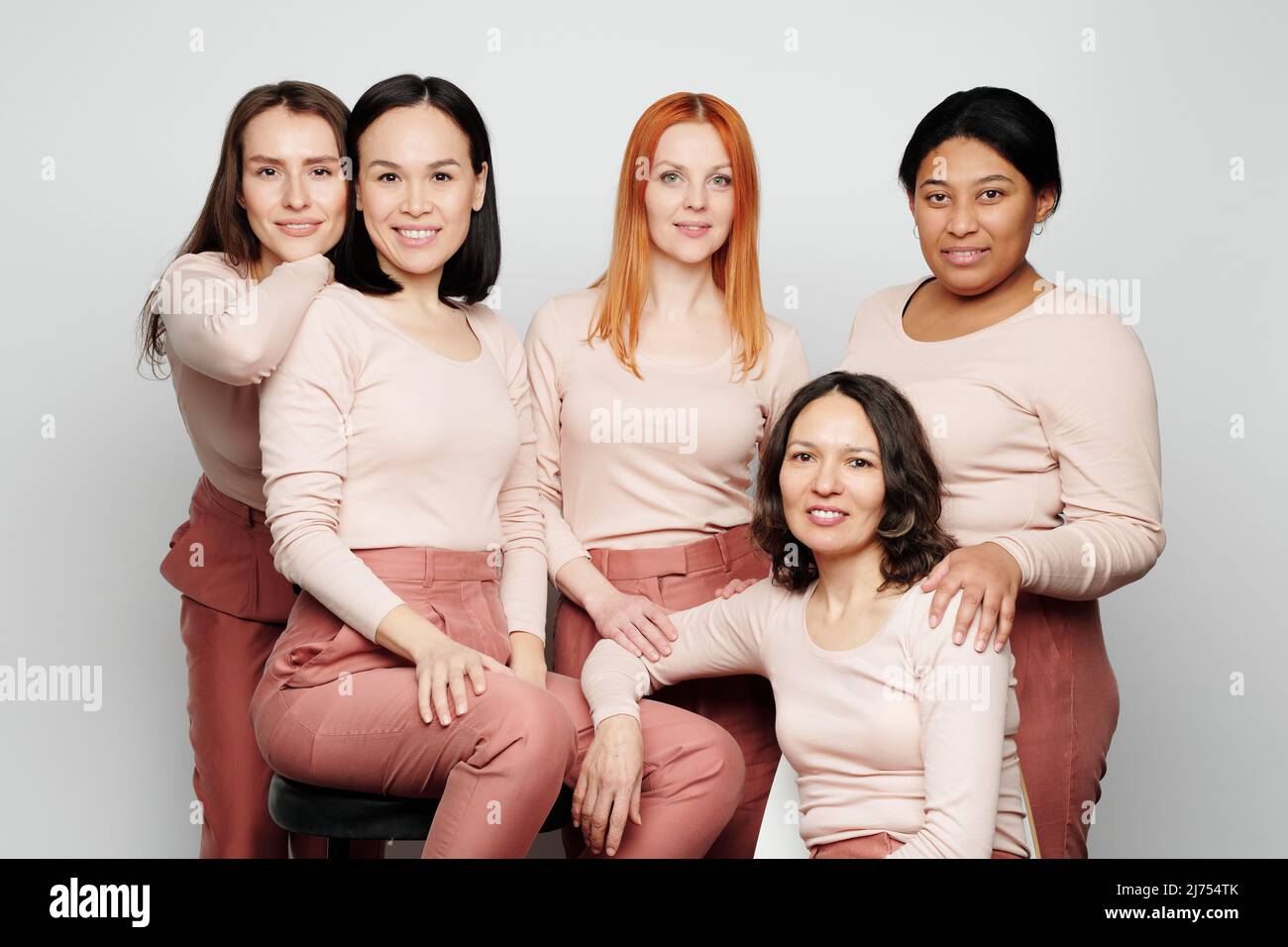 Group of bright and confident multi-ethnic ladies in same outfit posing ...