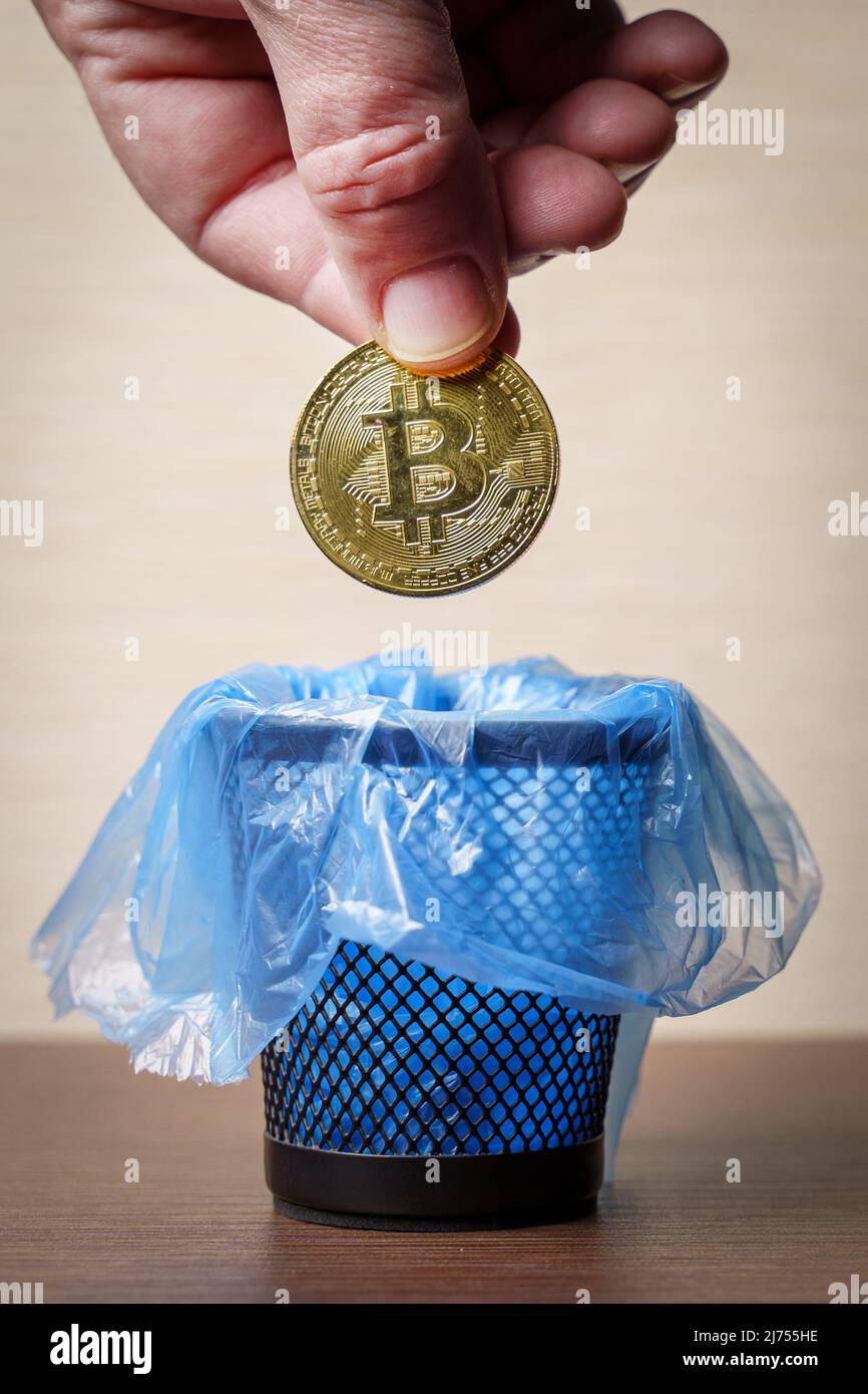 A man throws a bitcoin coin into a trash can, vertical shot Stock Photo ...