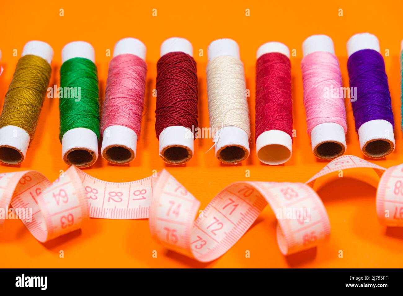 A set of multi-colored threads for sewing and a measuring tape on an ...