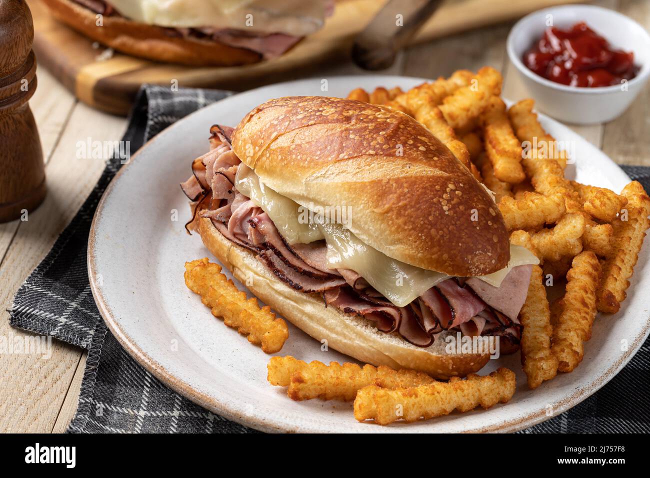 Hot ham and cheese submarine sandwich with french fries on a plate ...